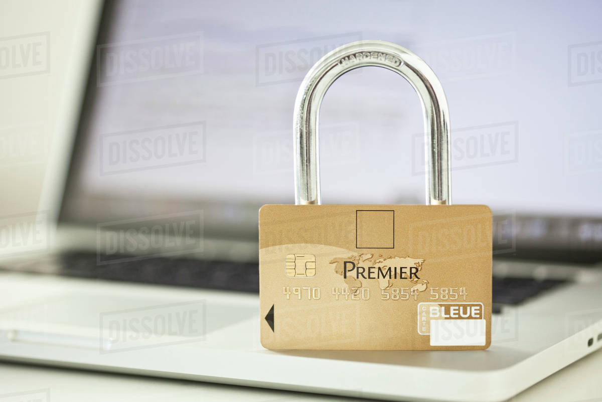 Credit card and lock resting on top of laptop computer representing ...