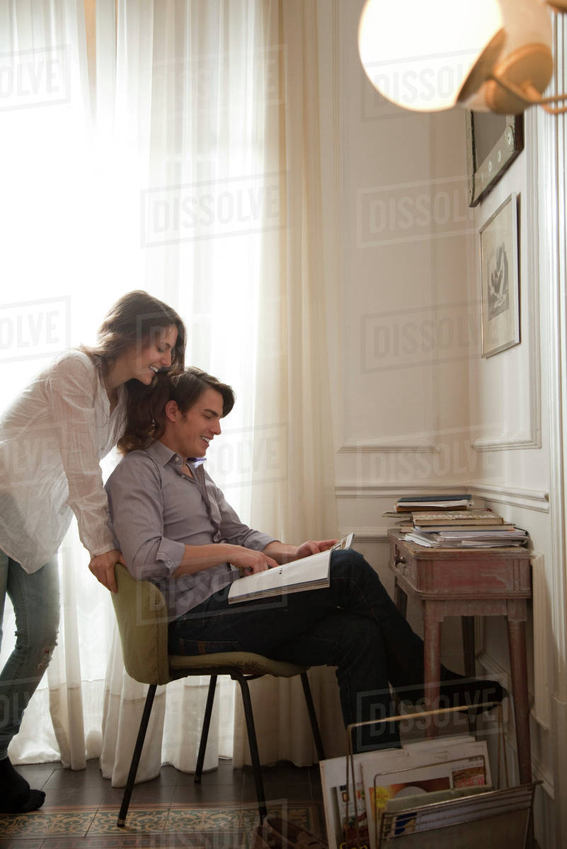 Couple looking at magazine together - Royalty-free Stock Photo | Dissolve
