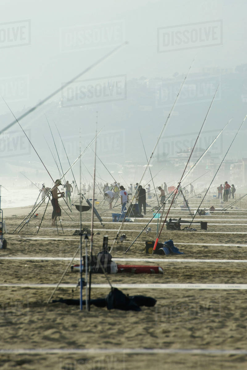 Crowd of people with fishing poles on beach - Stock Photo - Dissolve