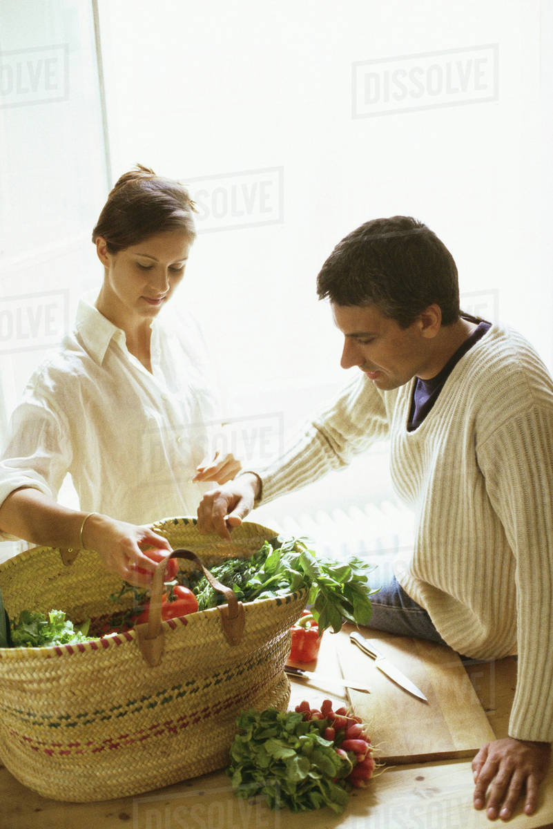 Couple removing fresh produce from basket - Stock Photo - Dissolve