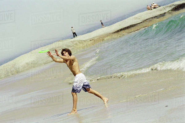 Male catching frisbee on beach - Royalty-free Stock Photo | Dissolve