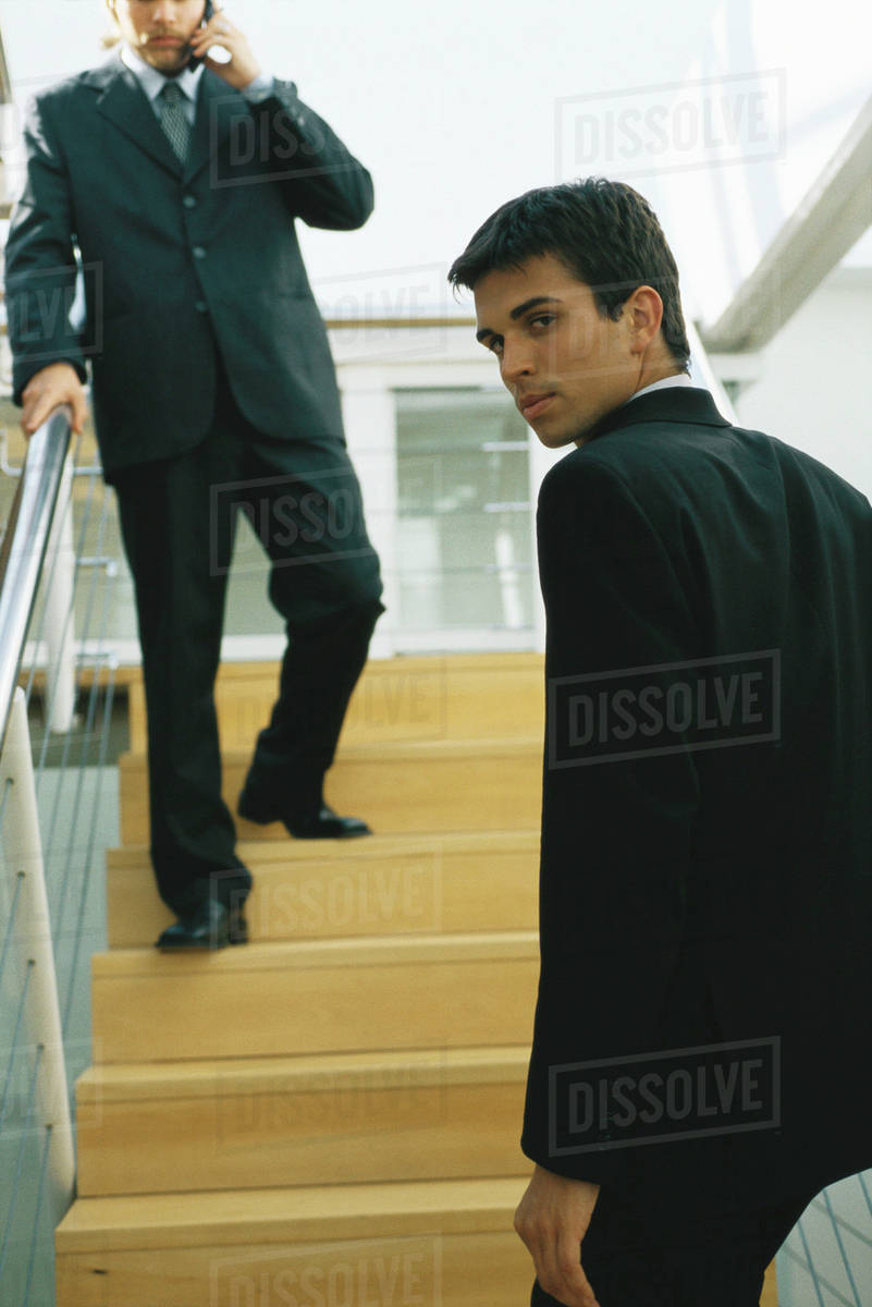 Businessman going up steps, looking over shoulder at camera - Royalty ...