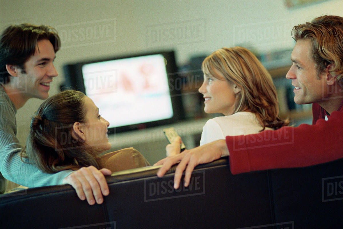 Two couples watching TV together, chatting, rear view - Royalty-free ...