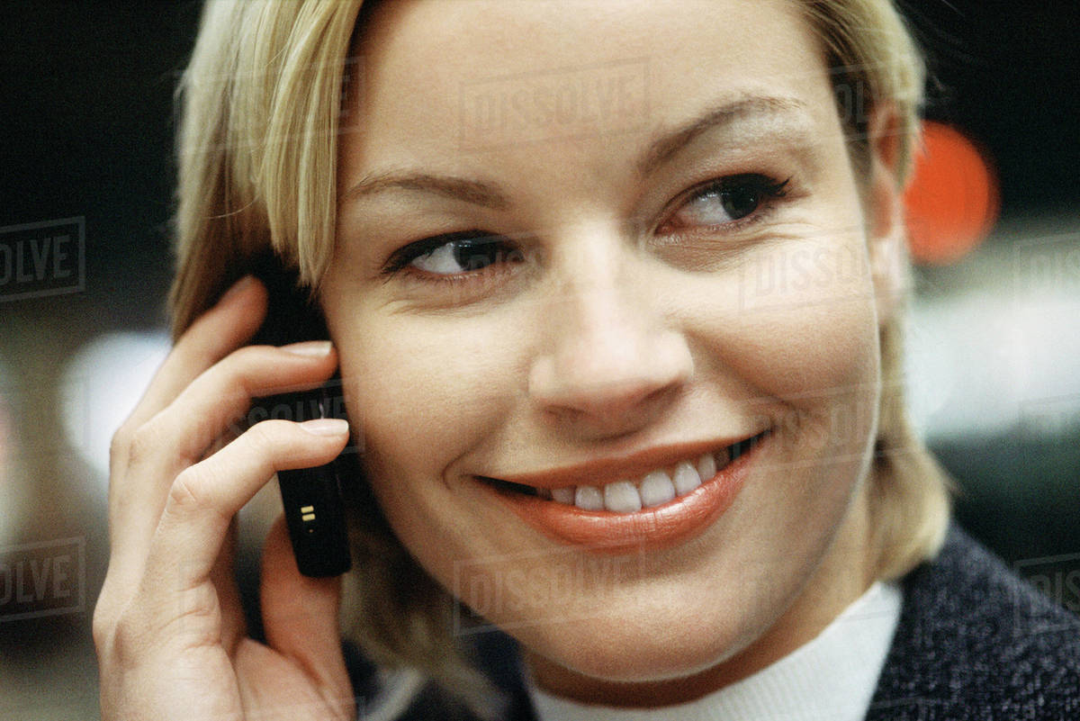 Woman phoning using cell phone smiling, glancing sideways, portrait ...