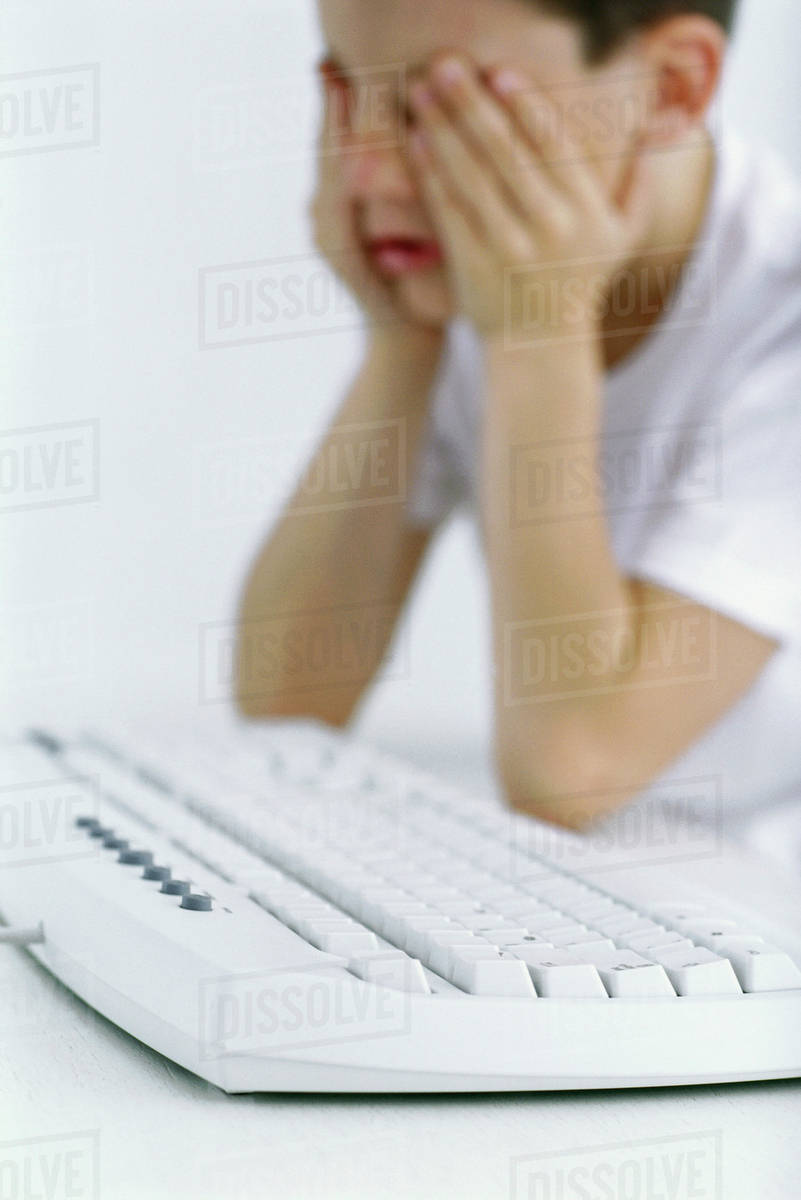 Boy holding head, computer keyboard in foreground - Royalty-free Stock ...