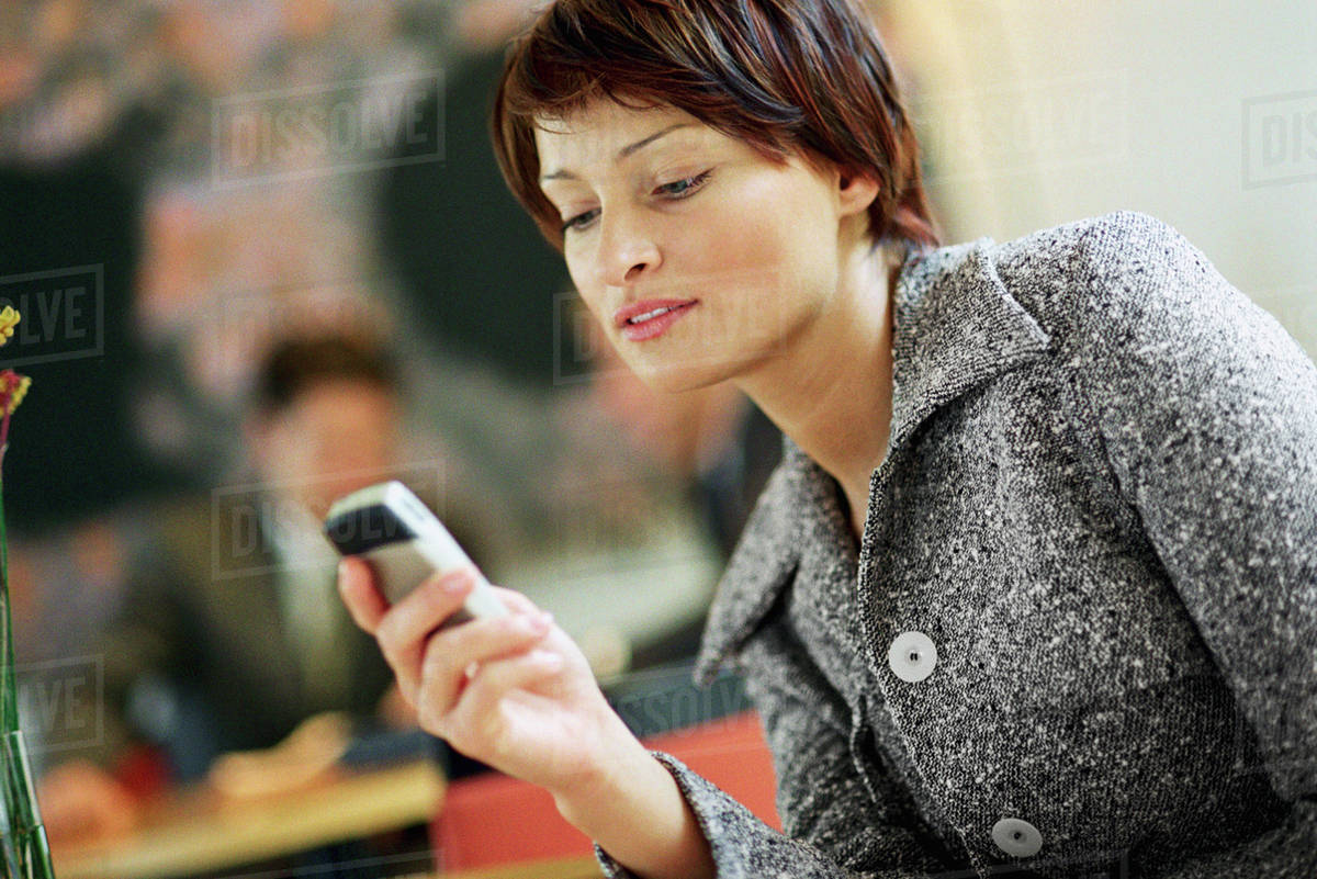 Businesswoman looking at cell phone - Royalty-free Stock Photo | Dissolve