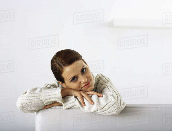 Woman leaning against armrest resting head on arms, portrait - Royalty ...