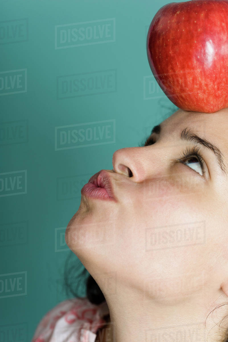 Woman balancing apple on forehead, puckering lips - Royalty-free Stock ...