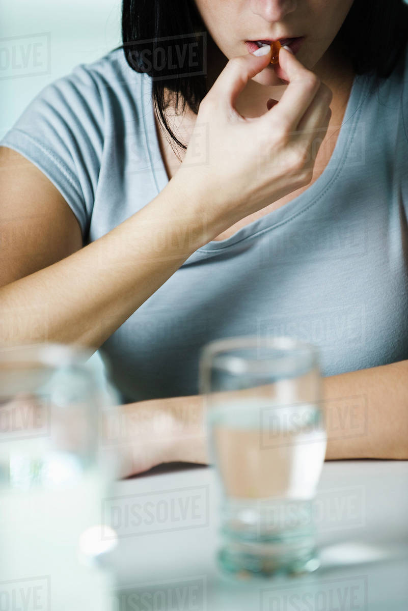 Woman taking vitamins, cropped - Royalty-free Stock Photo | Dissolve