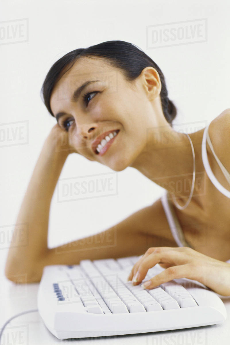 Woman leaning on elbow typing on keyboard, smiling - Royalty-free Stock ...