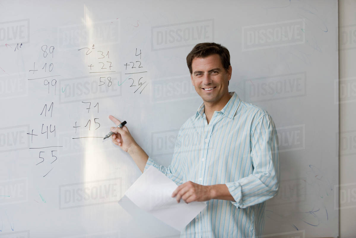 Math teacher pointing to arithmetic on whiteboard - Stock Photo - Dissolve