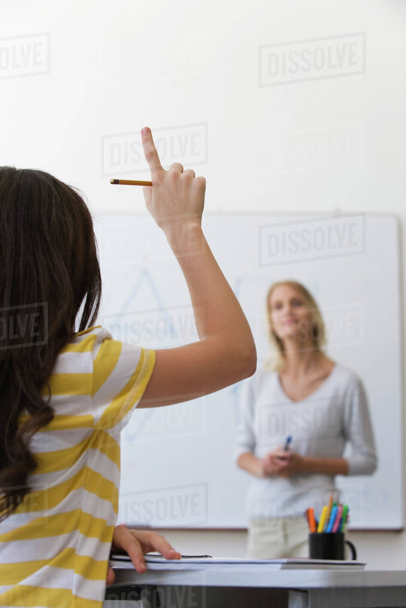 Female high school student raising hand in class - Stock Photo - Dissolve