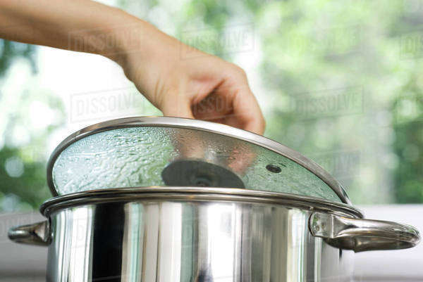 Person removing lid from cooking pot - Royalty-free Stock Photo | Dissolve