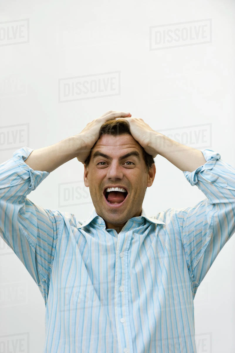 Man holding head screaming - Stock Photo - Dissolve