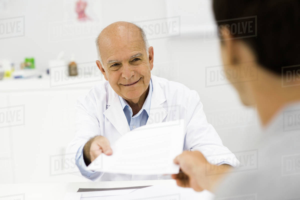 Doctor handing document to patient - Royalty-free Stock Photo | Dissolve