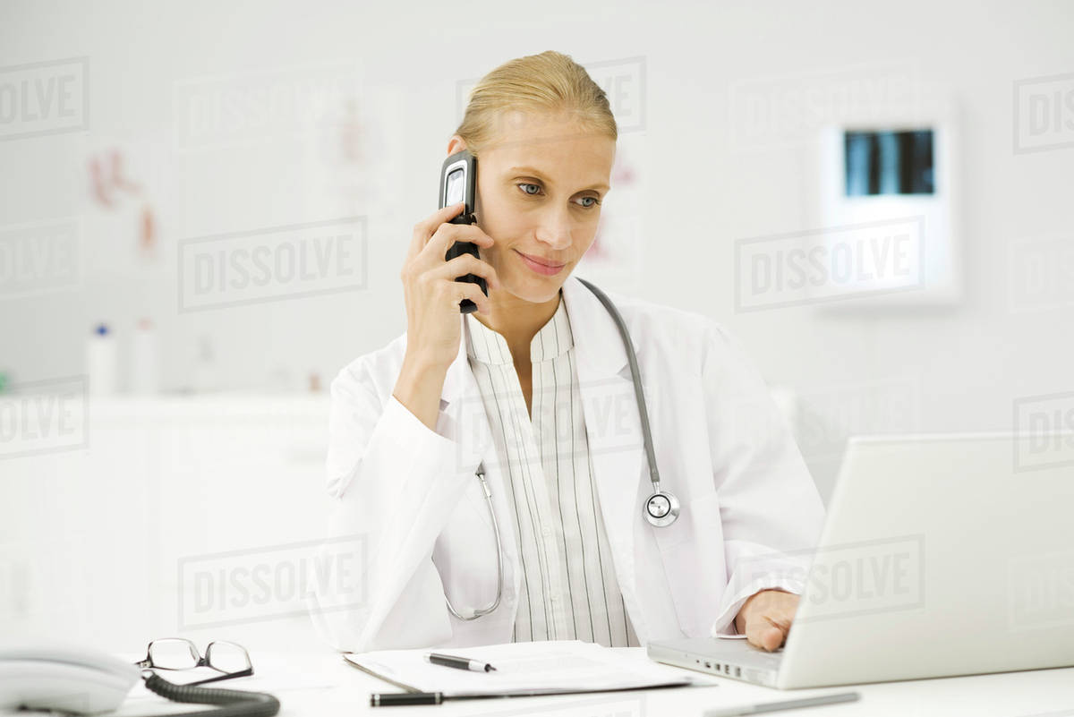 Female doctor multi-tasking at desk - Royalty-free Stock Photo | Dissolve