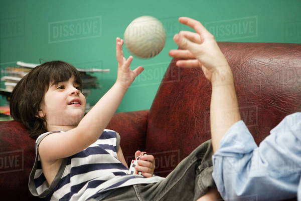 Little boy tossing ball with parent on sofa - Royalty-free Stock Photo ...