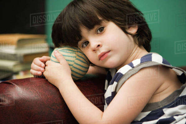 Little boy resting head on toy ball, portrait - Stock Photo - Dissolve
