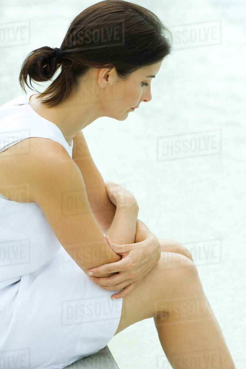 Woman sitting with arms folded, head down, side view - Royalty-free ...