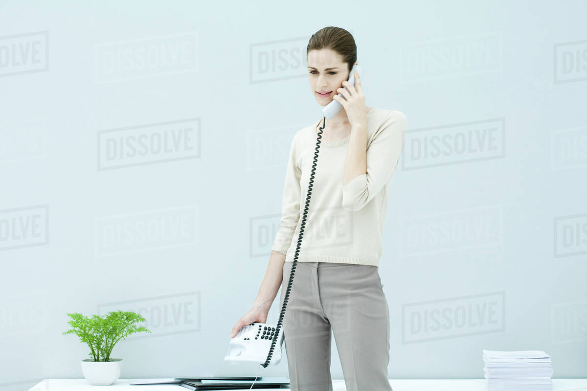 Young woman standing, using phone - Stock Photo - Dissolve