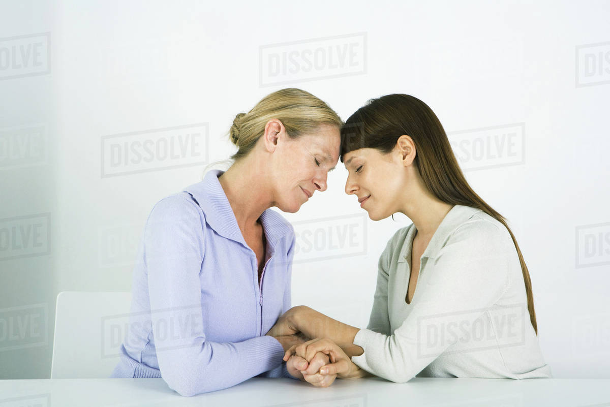 Two women holding hands, touching foreheads, eyes closed - Stock Photo ...
