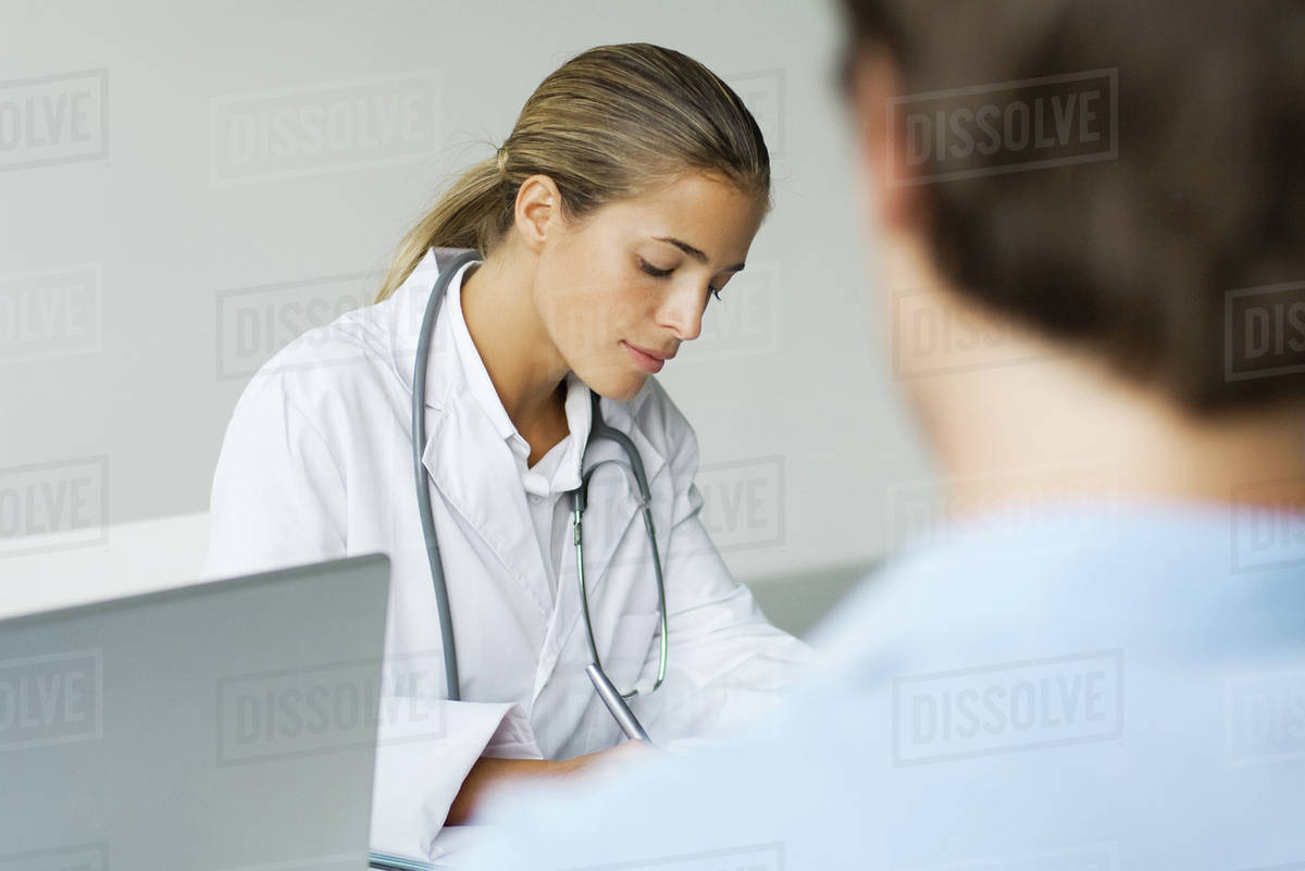Doctor writing at desk, patient in foreground - Royalty-free Stock ...