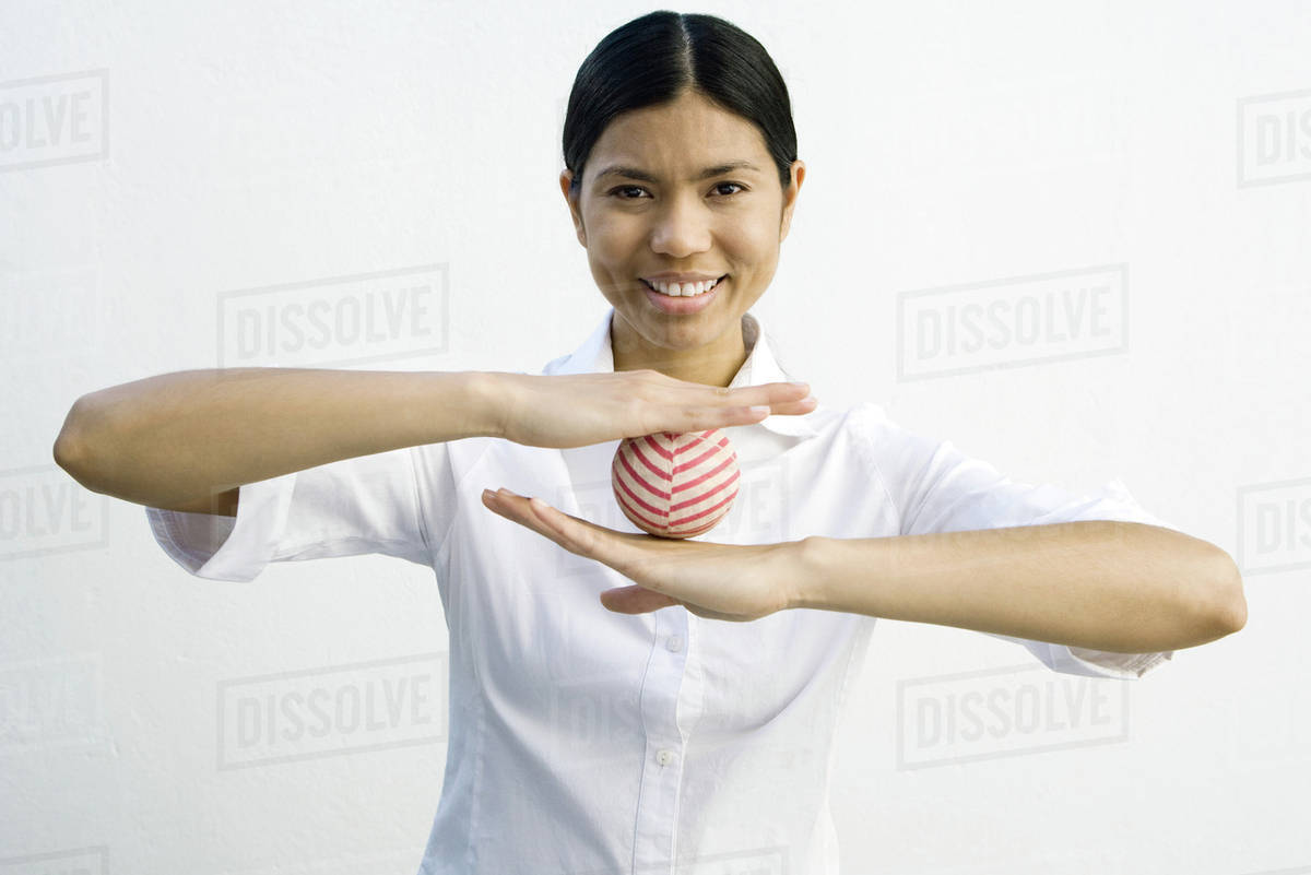 Woman balancing ball between her hands, smiling at camera - Royalty ...