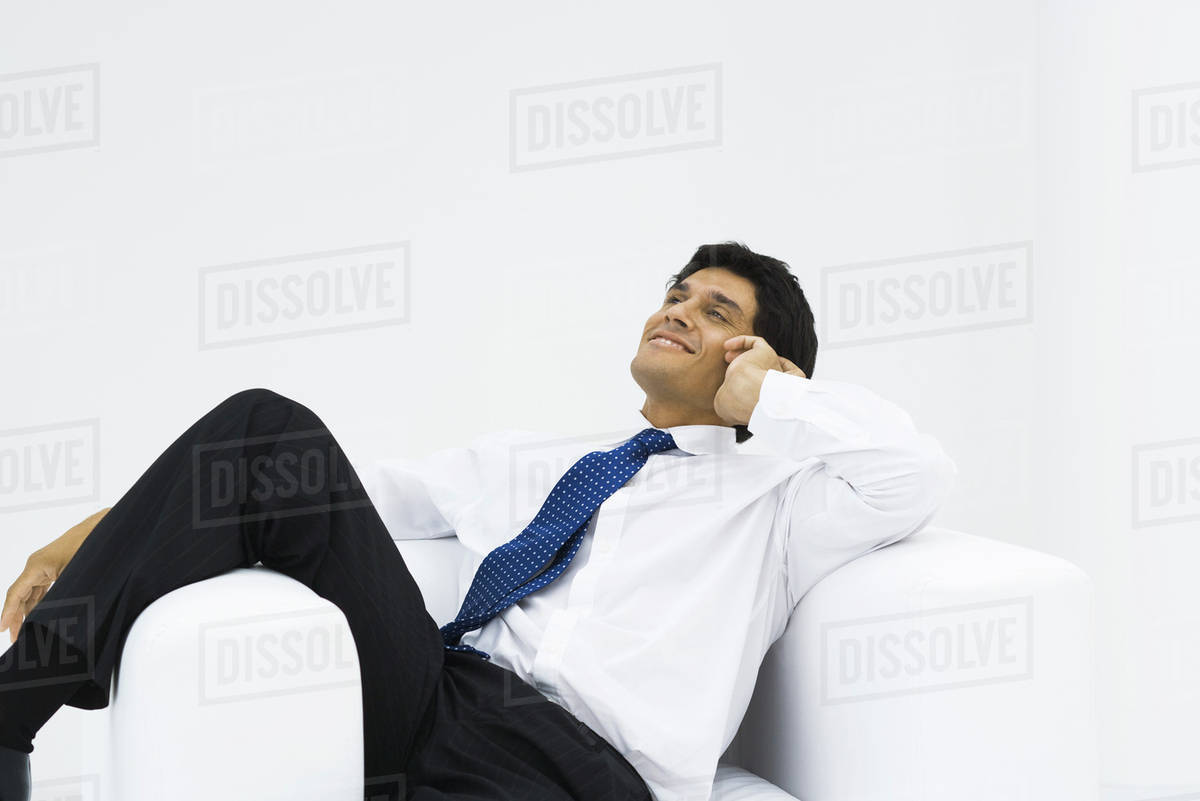Man reclining in armchair, holding head, smiling - Royalty-free Stock ...