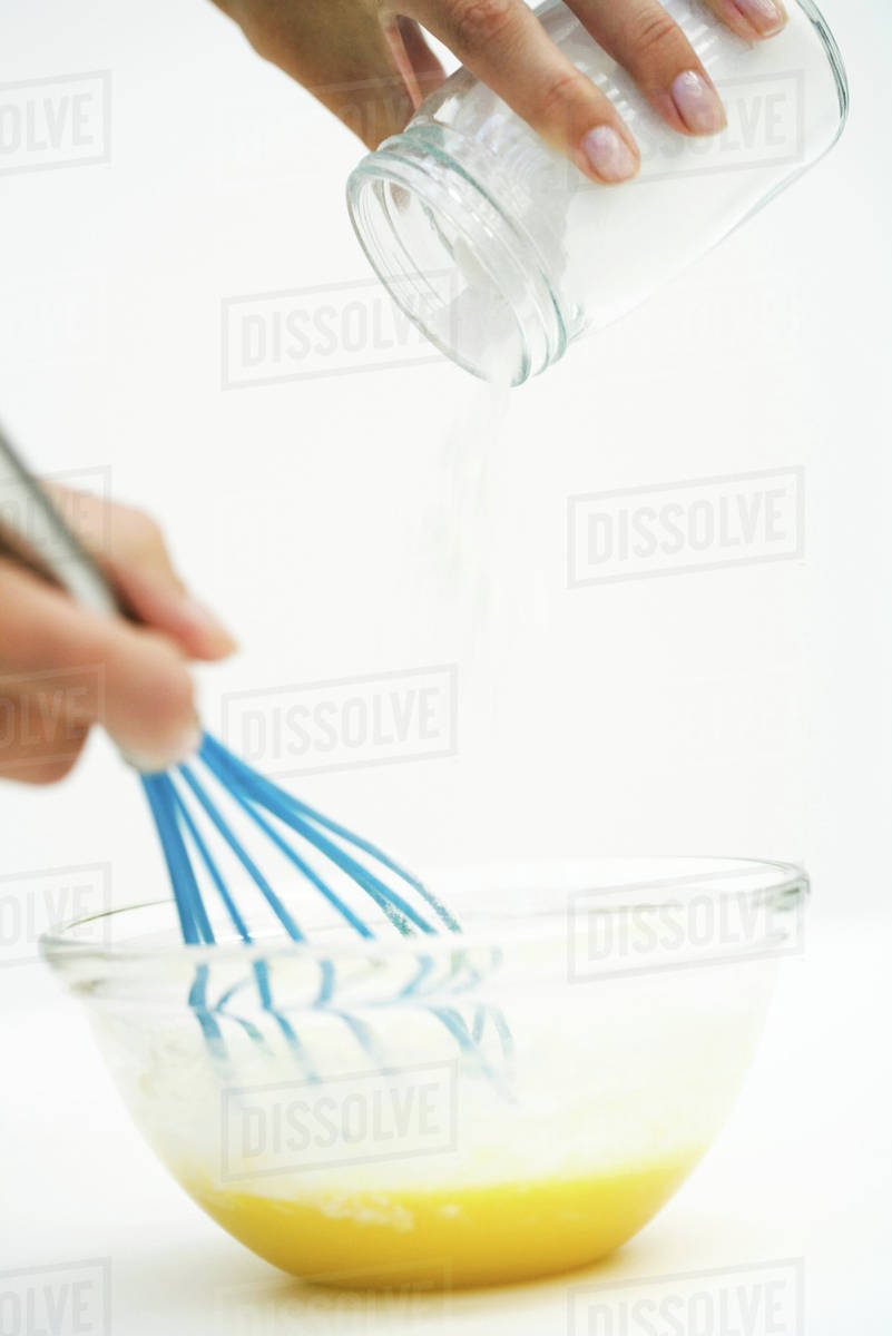Hand holding whisk, pouring flour into mixing bowl - Royalty-free Stock ...