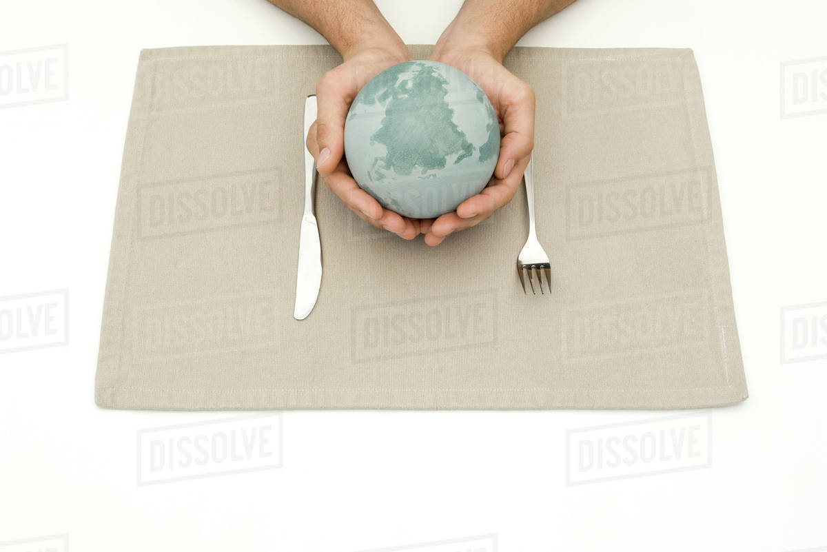 Hands holding globe over placemat and silverware - Royalty-free Stock ...
