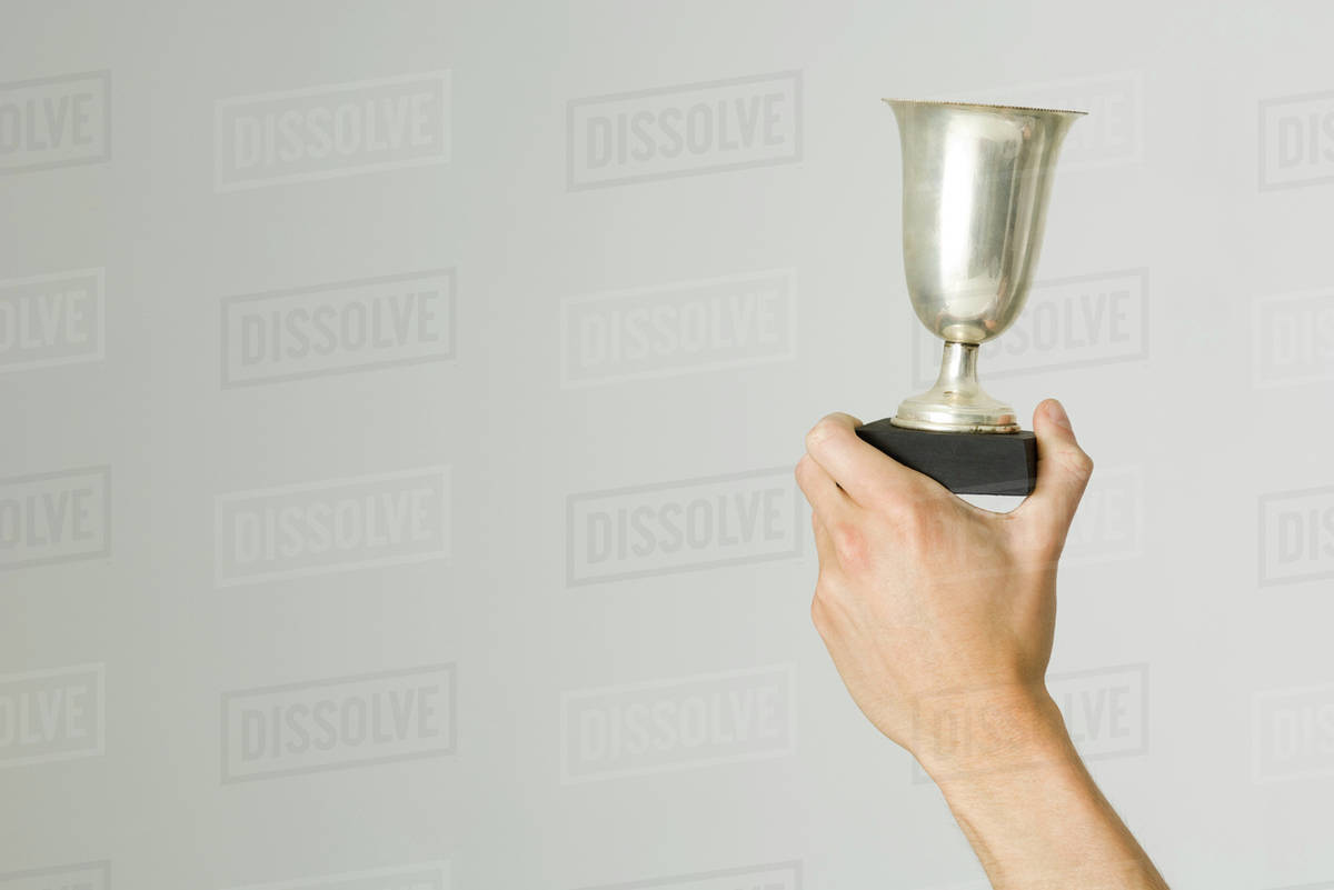 Hand holding up trophy, cropped view - Royalty-free Stock Photo | Dissolve