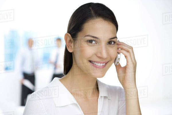 Professional woman using cell phone, smiling at camera - Royalty-free ...