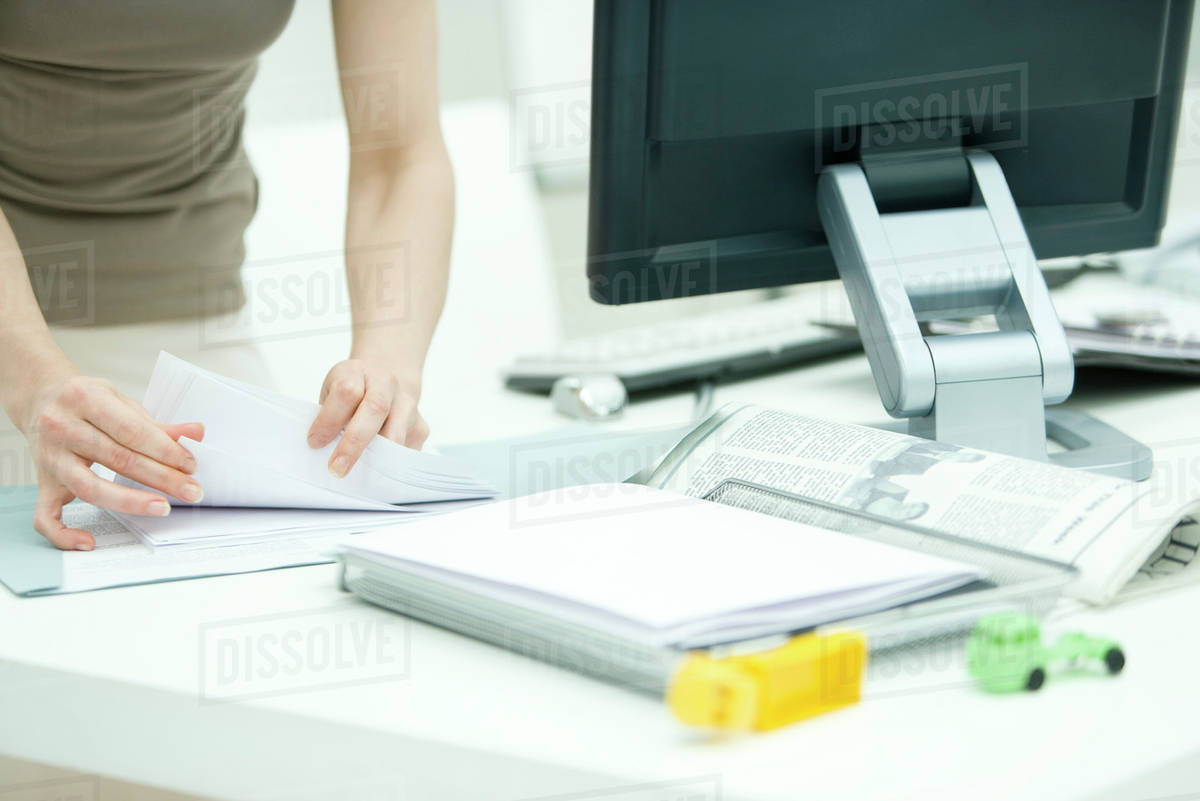 Woman sorting through documents on desk, child's toys in foreground ...