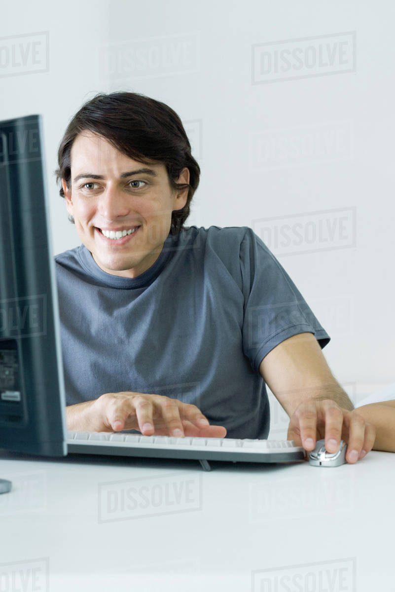 Man using desktop computer, smiling - Royalty-free Stock Photo | Dissolve