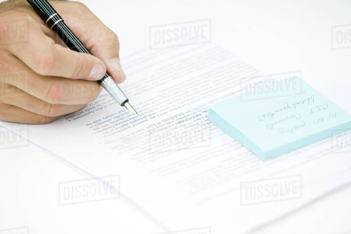 Hand holding pen, editing document - Stock Photo - Dissolve