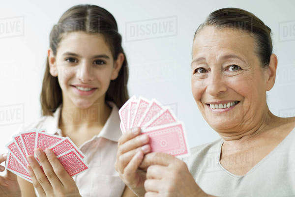 Grandmother and granddaughter playing cards, smiling at camera ...