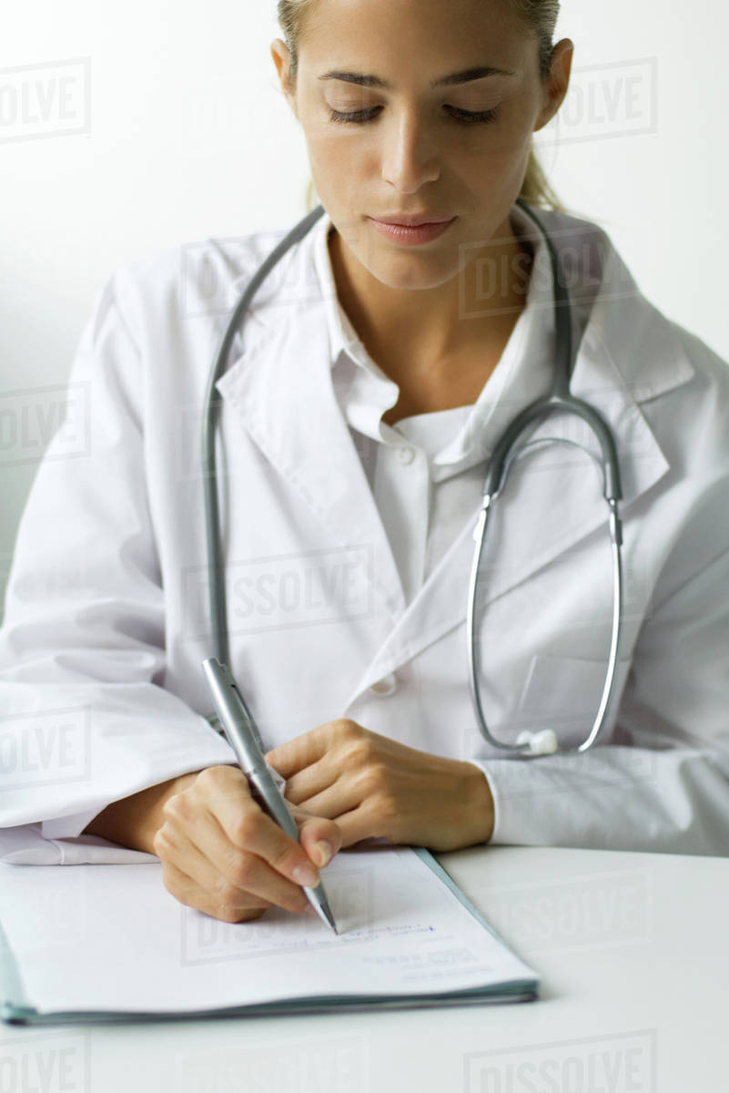Doctor writing at desk - Royalty-free Stock Photo | Dissolve