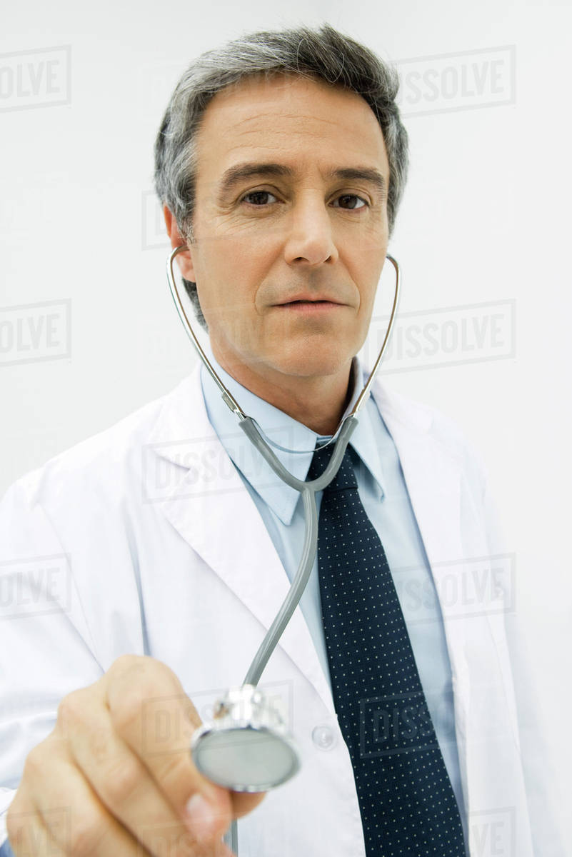 Doctor holding stethoscope toward camera, focus on background - Stock ...