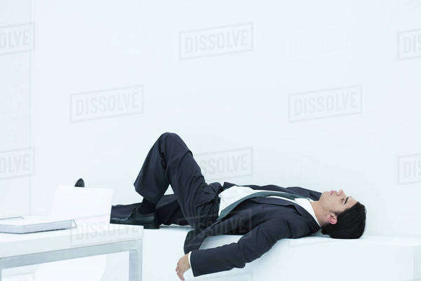 Businessman lying down on ledge in office - Royalty-free Stock Photo ...
