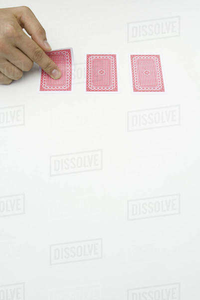 Hand turning over one of three cards - Royalty-free Stock Photo | Dissolve