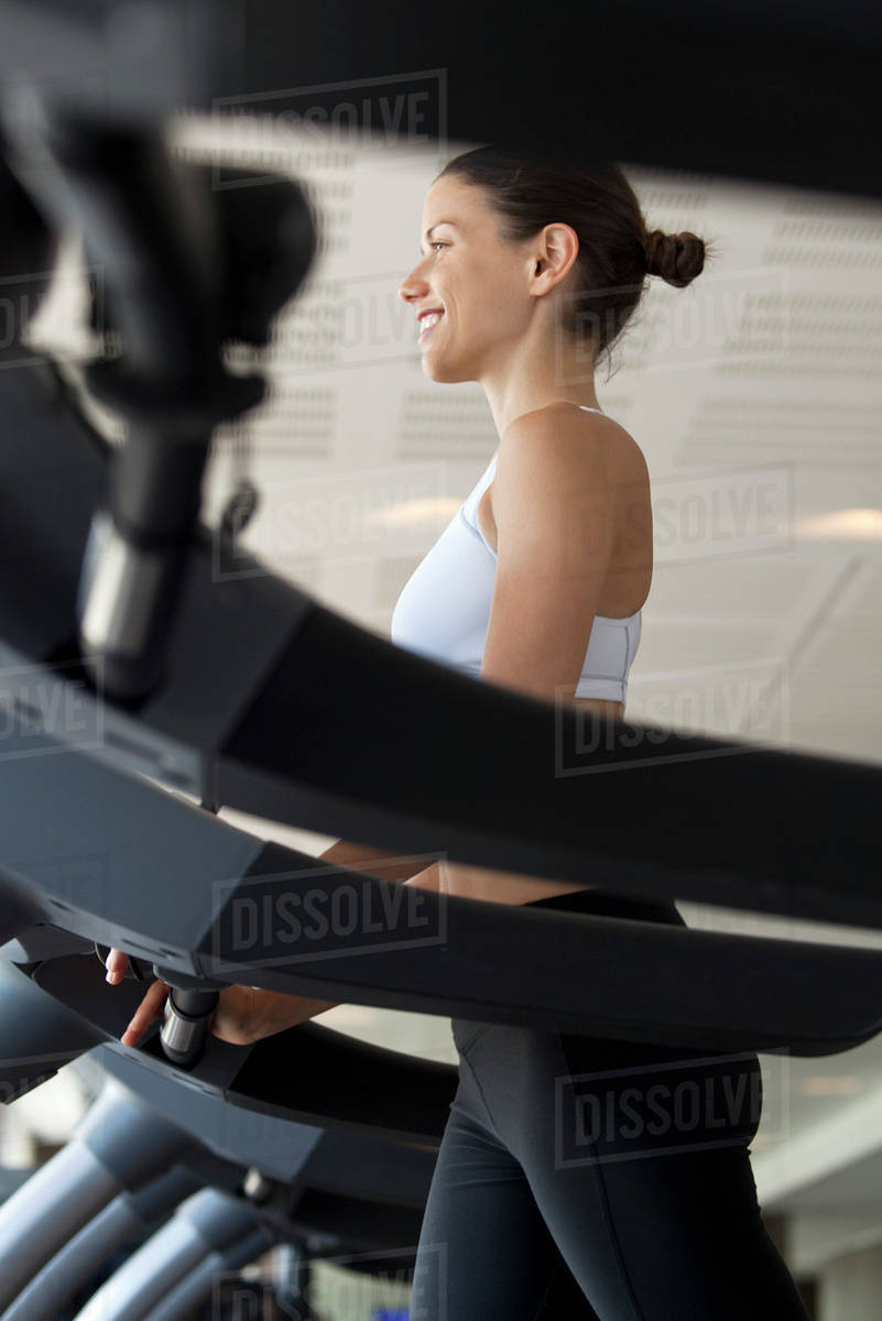 Woman on exercise machine at gym - Stock Photo - Dissolve