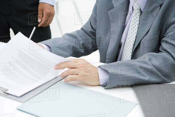 Businessman reviewing document at desk, cropped view - Royalty-free ...