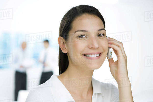 Professional woman using cell phone, smiling at camera - Royalty-free ...