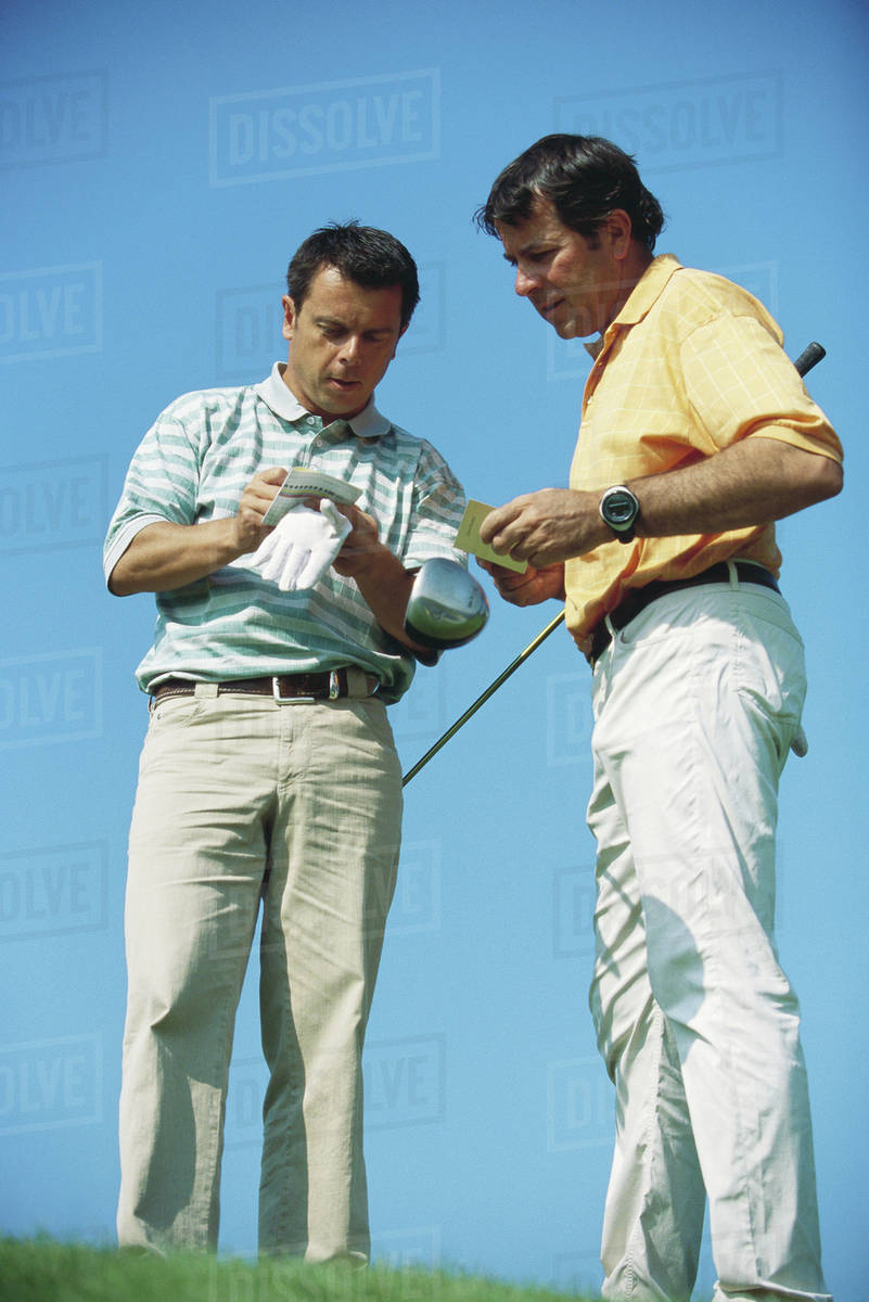 Two golfers, noting score, full length - Stock Photo - Dissolve