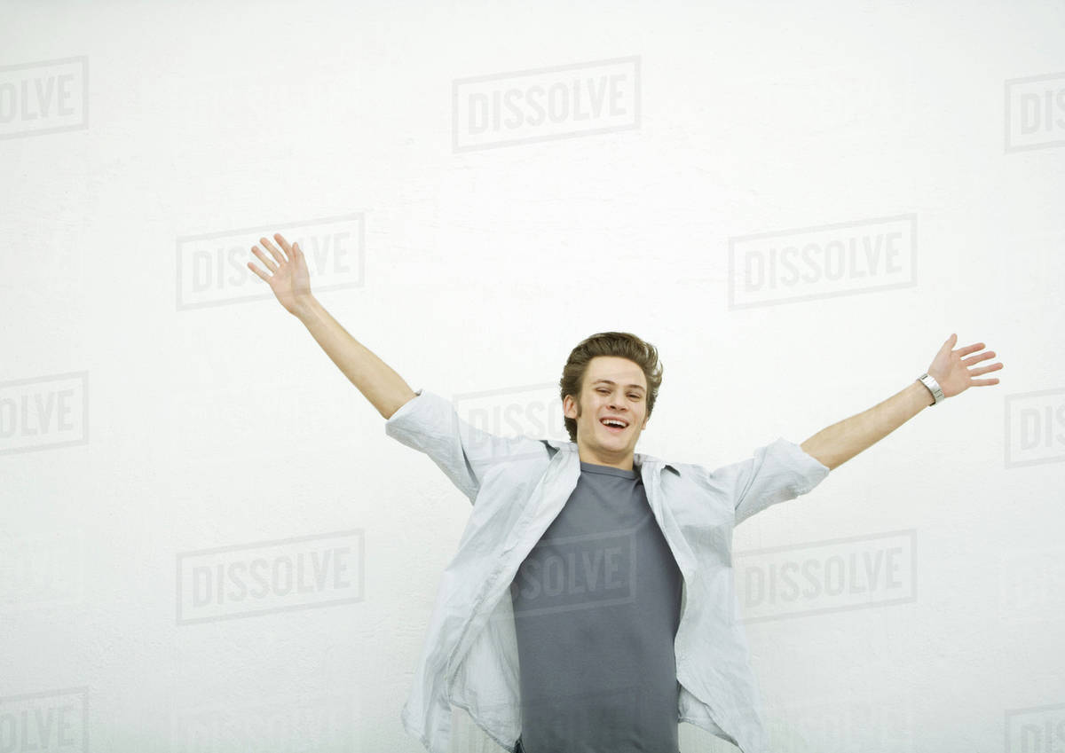 Young man standing with arms up, smiling, portrait - Royalty-free Stock ...