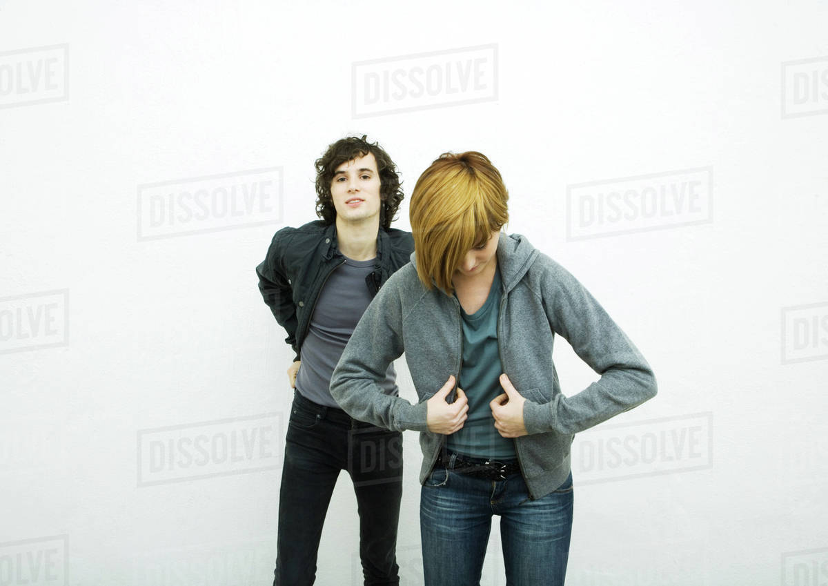 Two young adults putting on jackets, white background - Stock Photo ...
