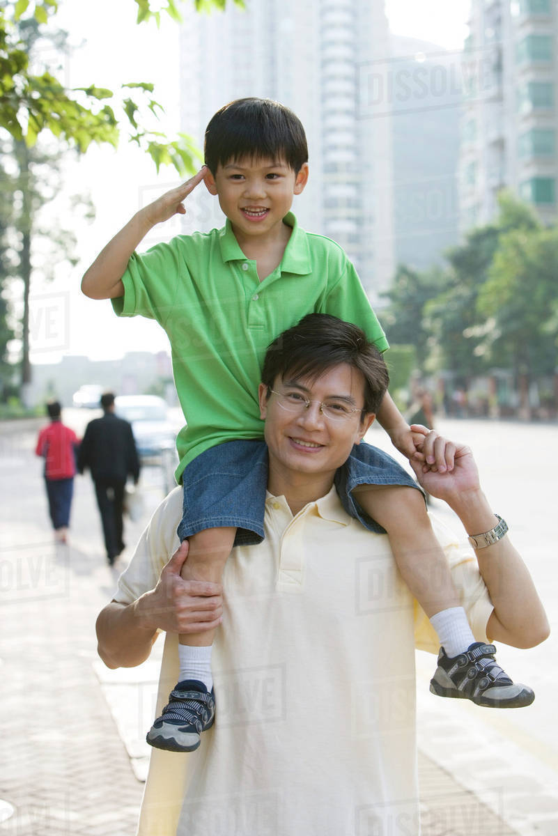 Boy riding on father's shoulders, saluting camera - Royalty-free Stock ...