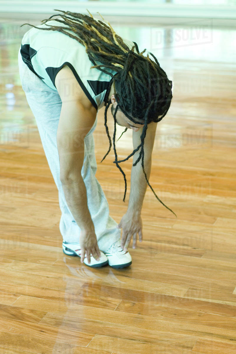 Man doing standing forward bend, full length - Stock Photo - Dissolve
