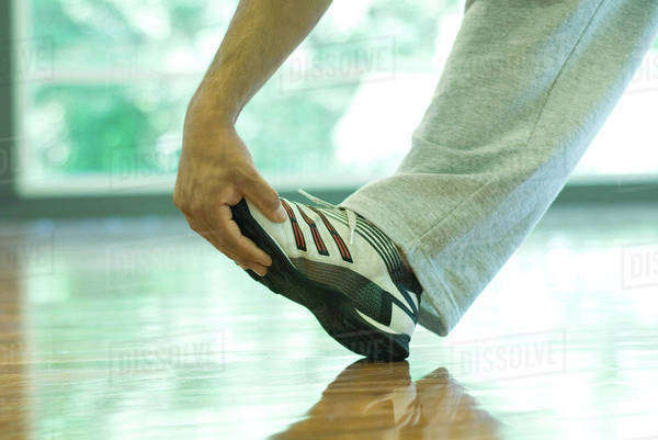 Man touching toe, close-up - Stock Photo - Dissolve