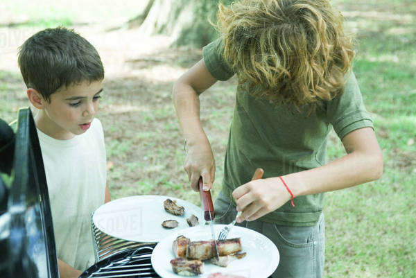 Boy cutting up meat on plate while second boy watches - Royalty-free ...